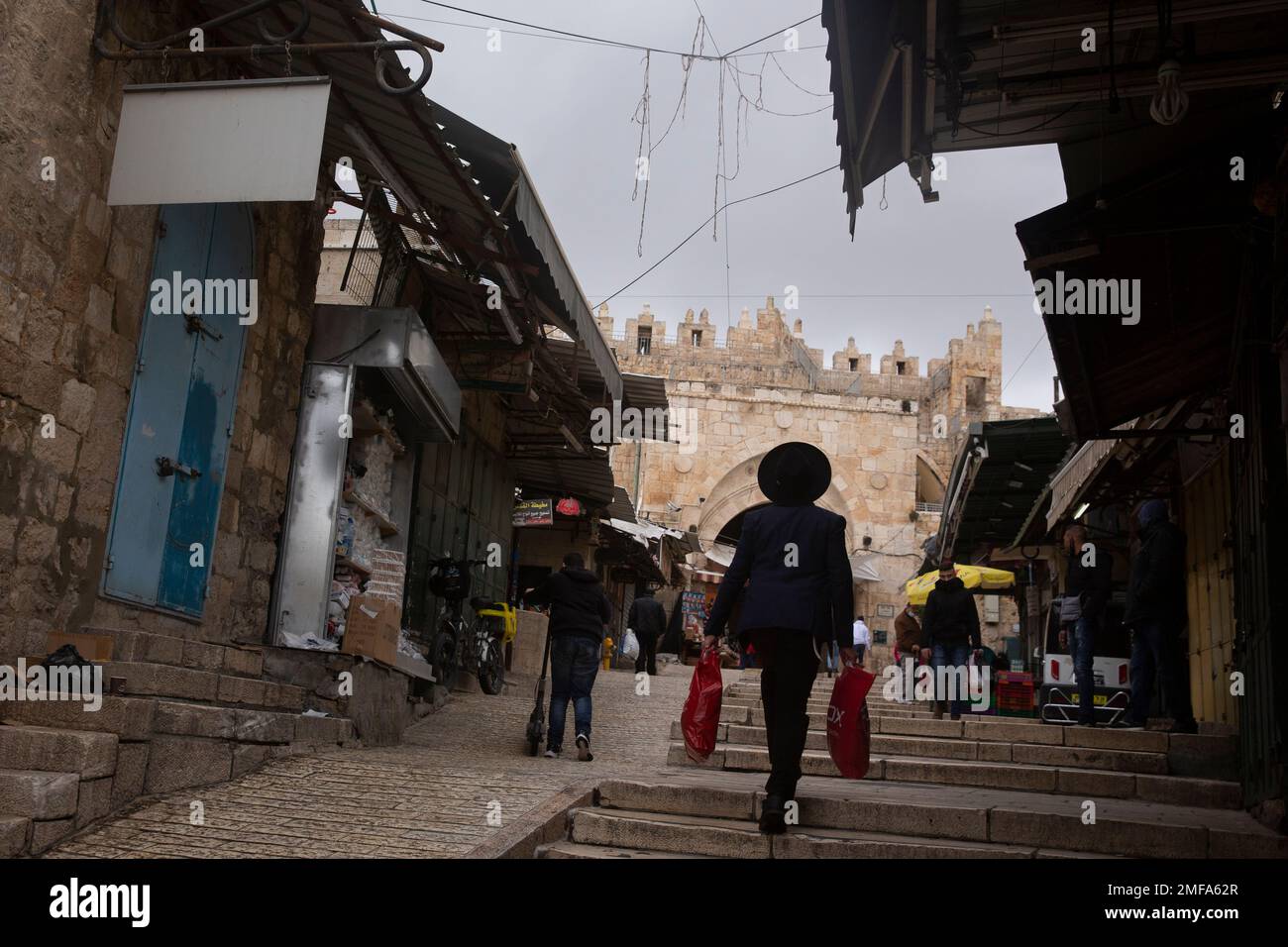 Shoppers walk pass shopkeepers near the Damascus Gate in the Old City ...