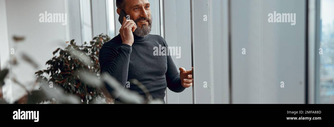 Smiling man using mobile phone while talking Stock Photo - Alamy