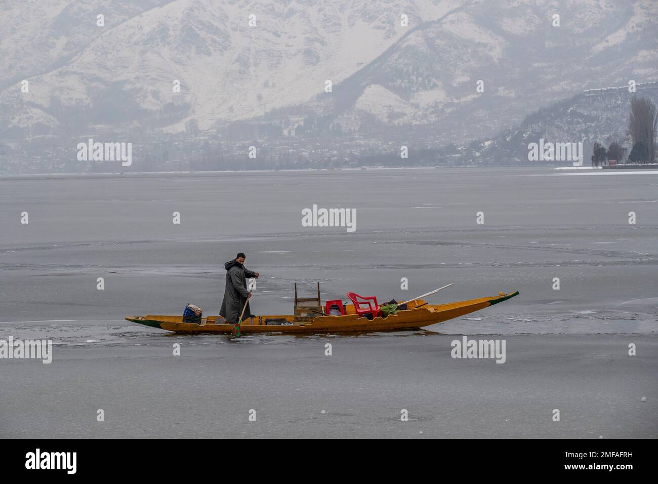 A Kashmiri boat man makes his way through the frozen surface of the Dal ...