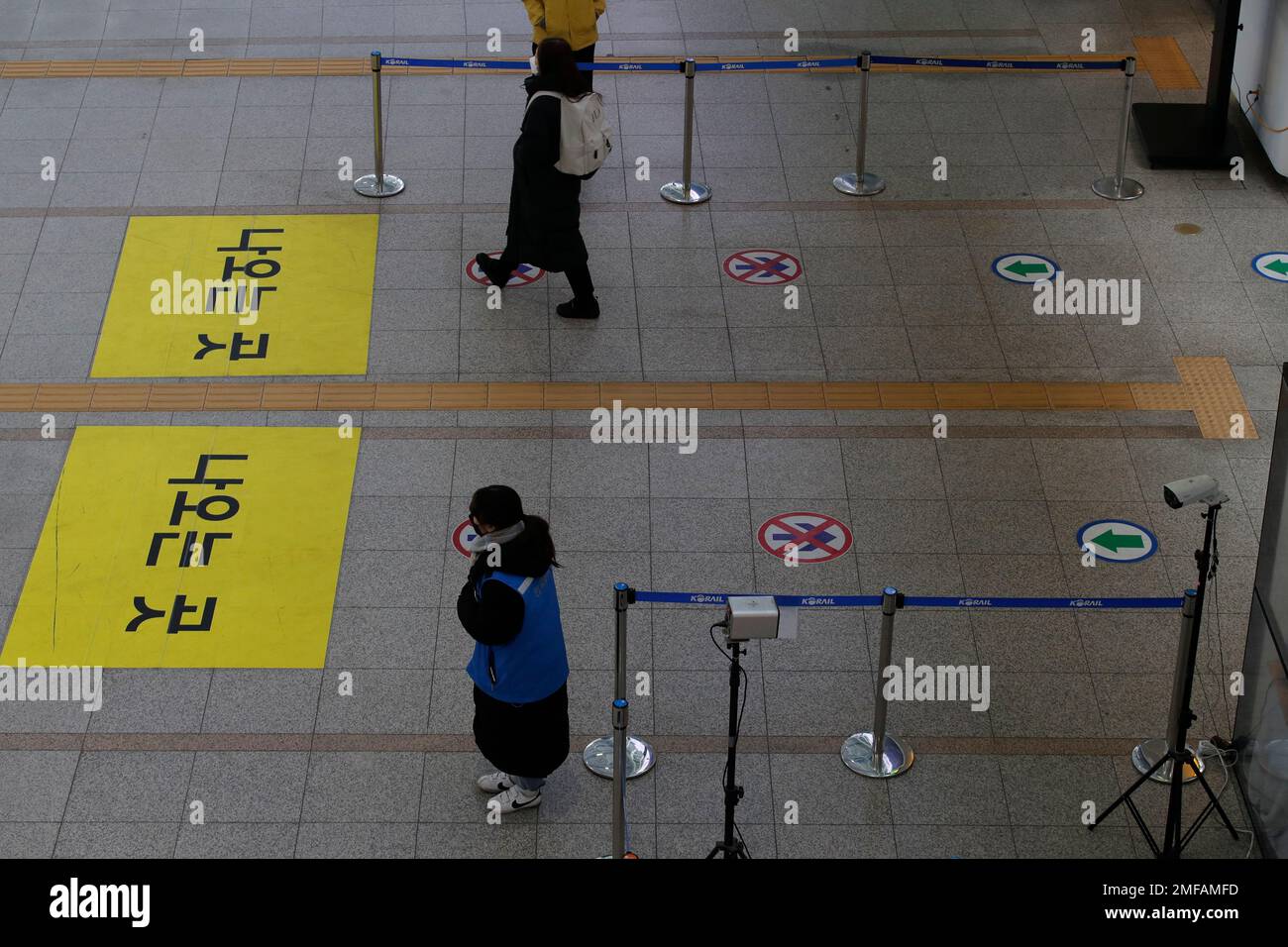 An employee wearing a face mask stands to guide passengers to maintain ...