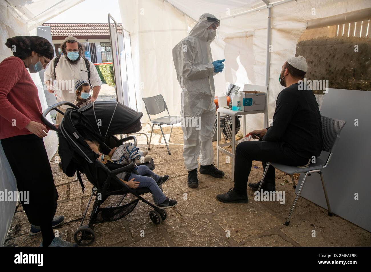 People wait to be tested for COVID-19 by an Israeli health care ...