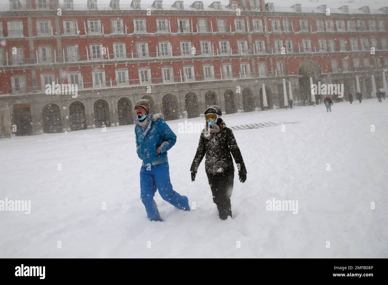 People walk crossing the Plaza Mayor during a heavy snowfall in Madrid ...