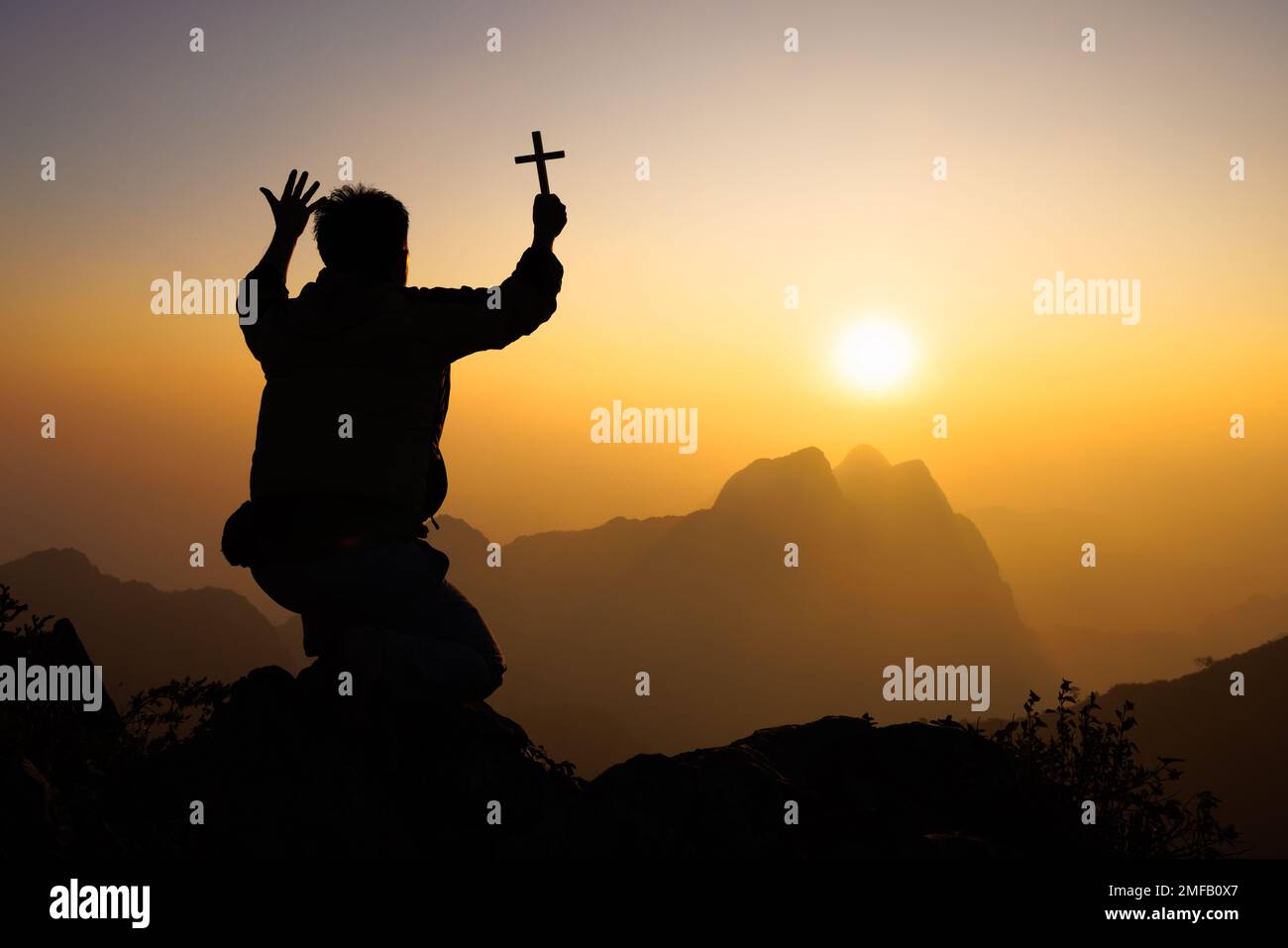 Silhouette of christian man praying with a cross at sunrise, Christian ...