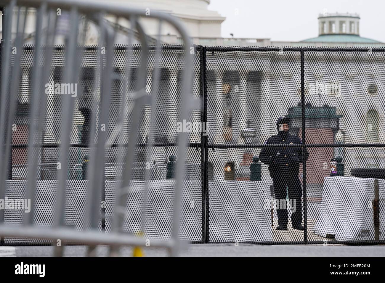 A member of the U.S. Capitol Police stands behind security fencing ...