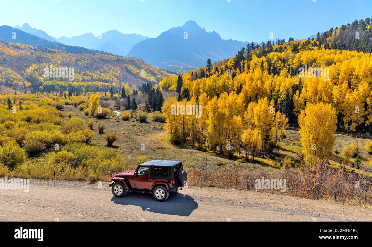 Autumn Valley - A red Jeep/SUV exploring in a colorful valley at base ...