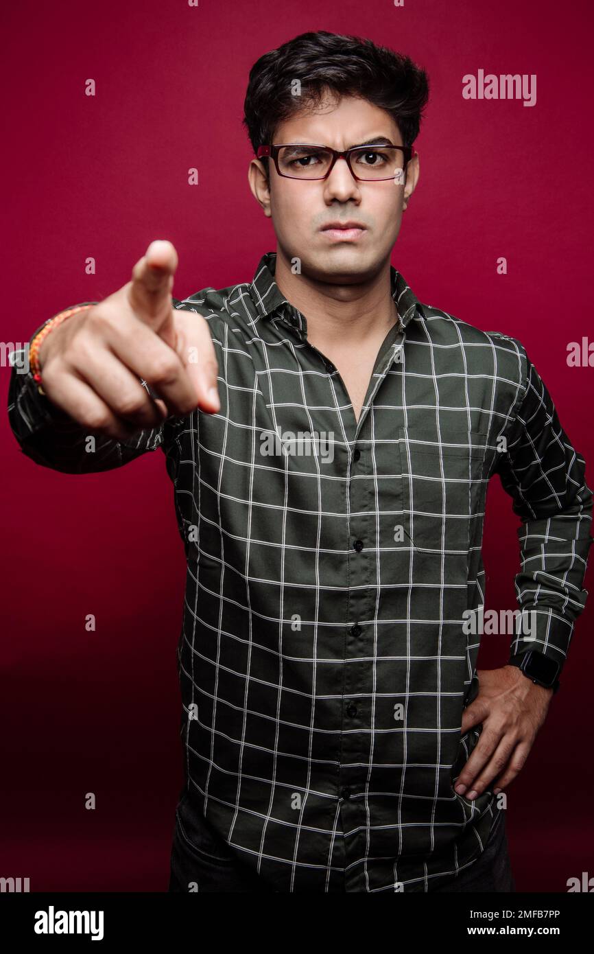 Angry young man pointing finger at you in accusation, saying it’s your fault on a studio ...