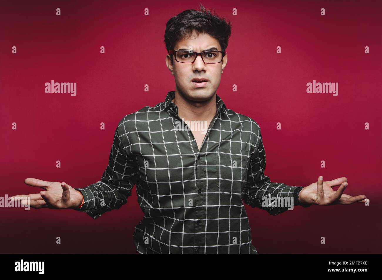 A man displaying a surprised expression with both hands raised in a ...