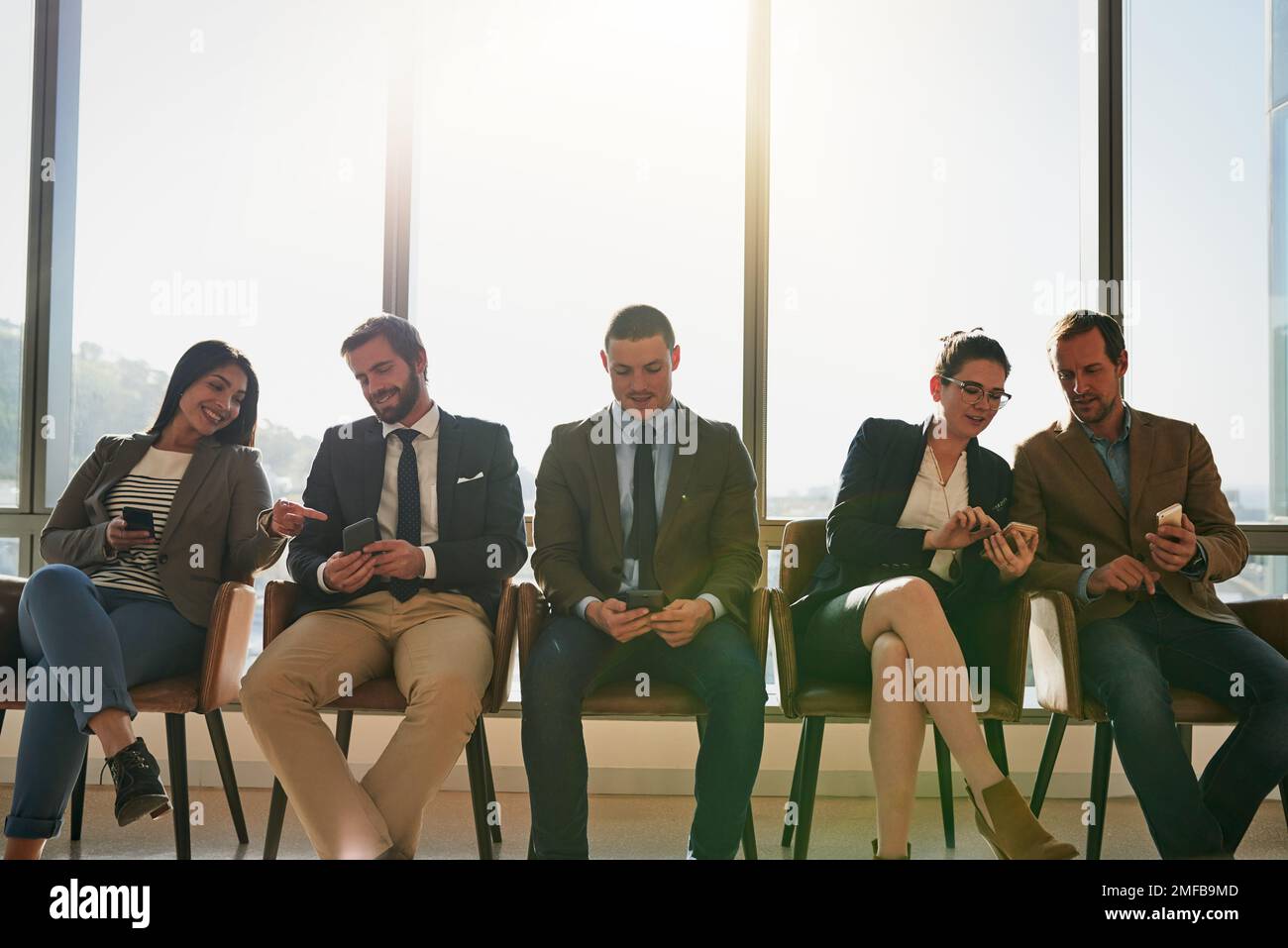 Chatting while they wait. a group of businesspeople sitting in line ...