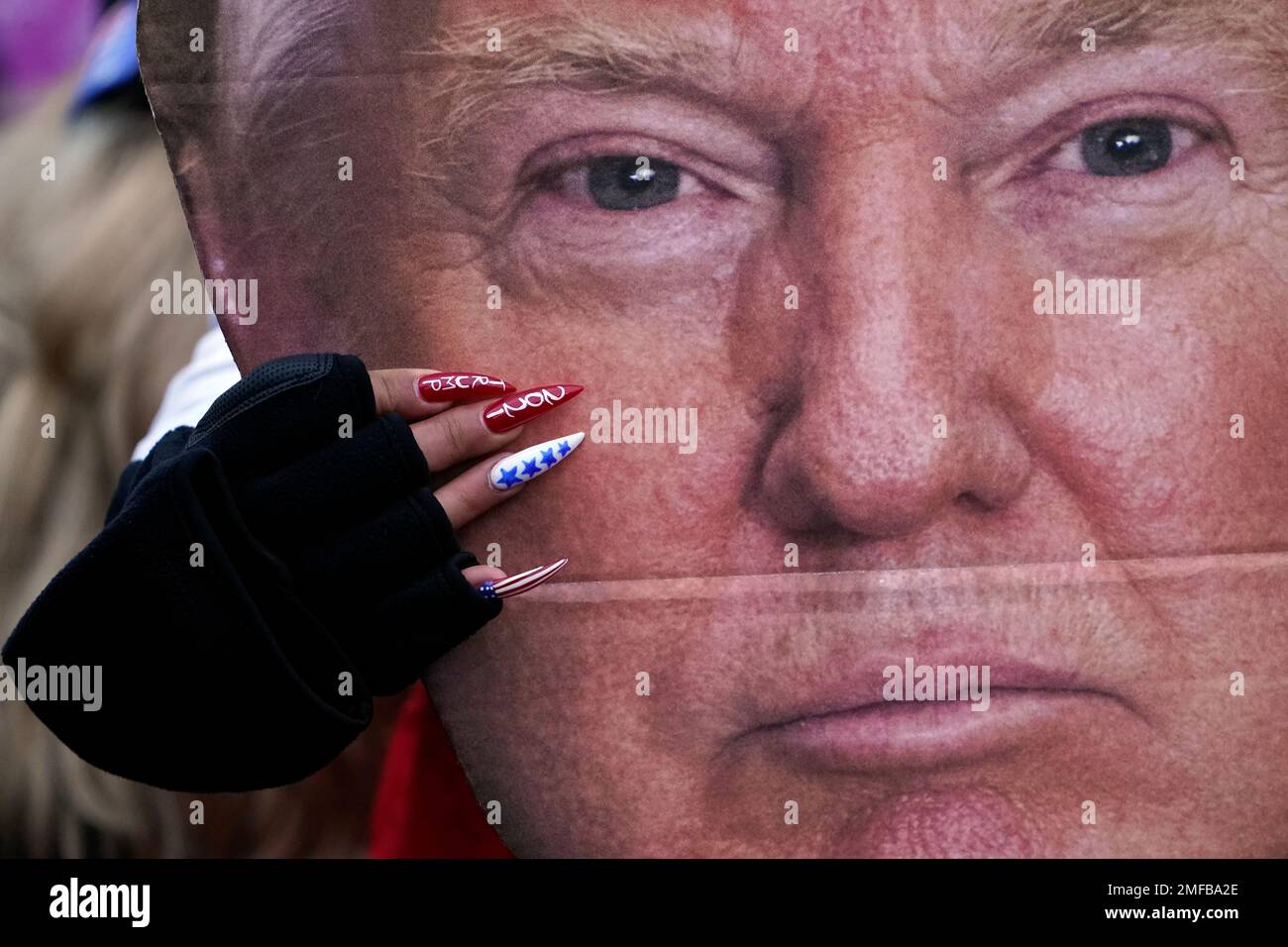 A woman holds a cut out of President Donald Trump's face Wednesday, Jan ...