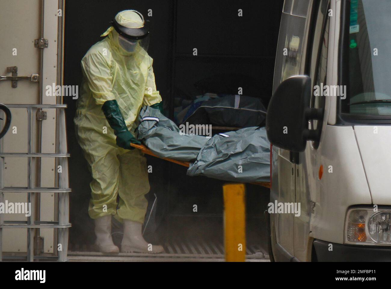 Health workers remove the body of a COVID-19 victim from a container ...
