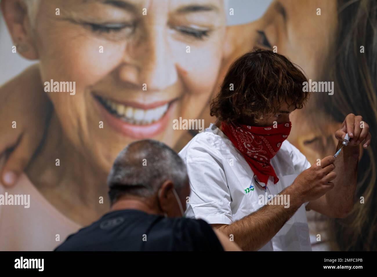 A medical staff member prepares a syringe to administer the coronavirus ...