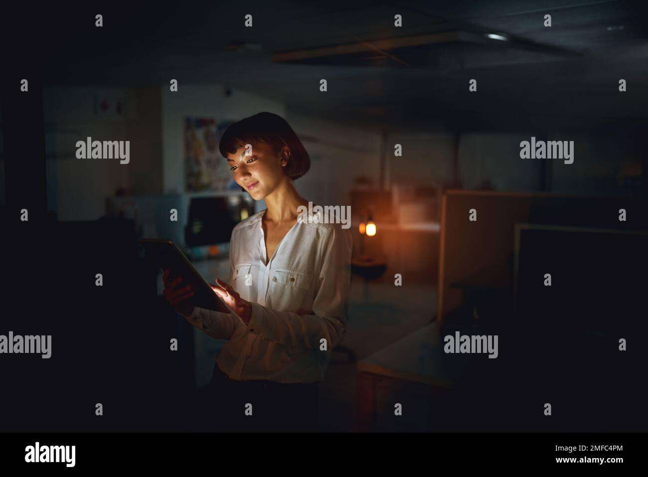 Overtime comes with the job description. a young businesswoman using a ...