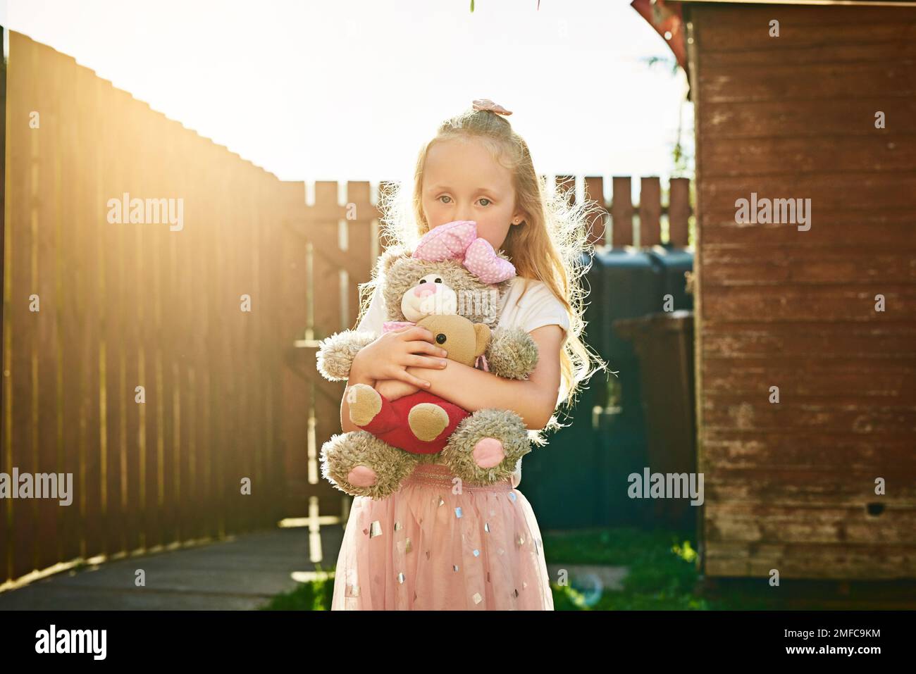 Teddy is my best friend. Portrait of cheerful little girl standing and holding her stuffed ...