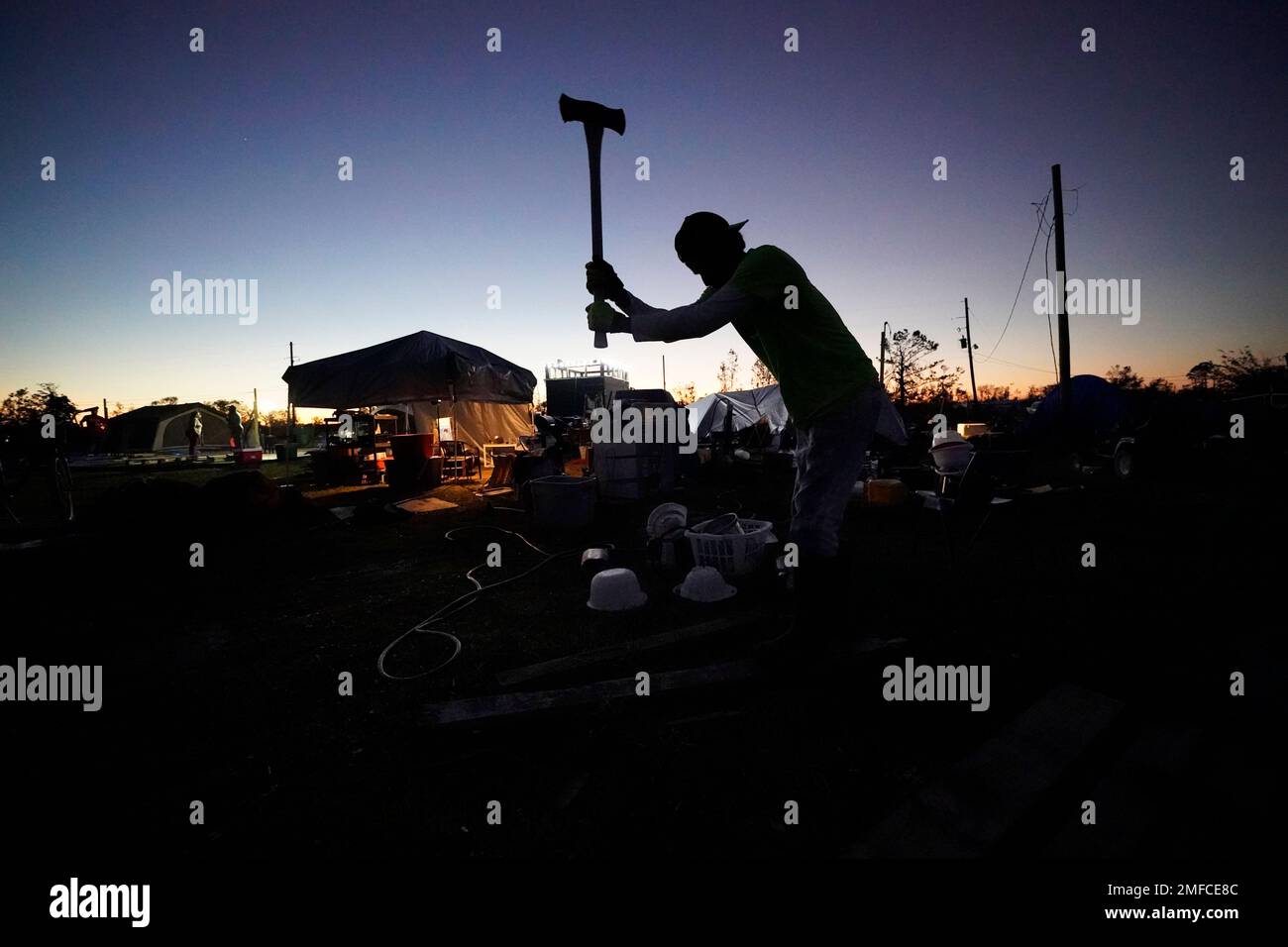 Ricky Trahan chops wood to make a fire on his property after their home ...