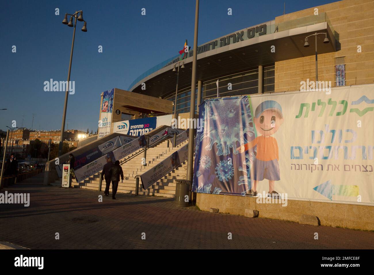 A couple enters a sports arena to receive the coronavirus vaccine in ...