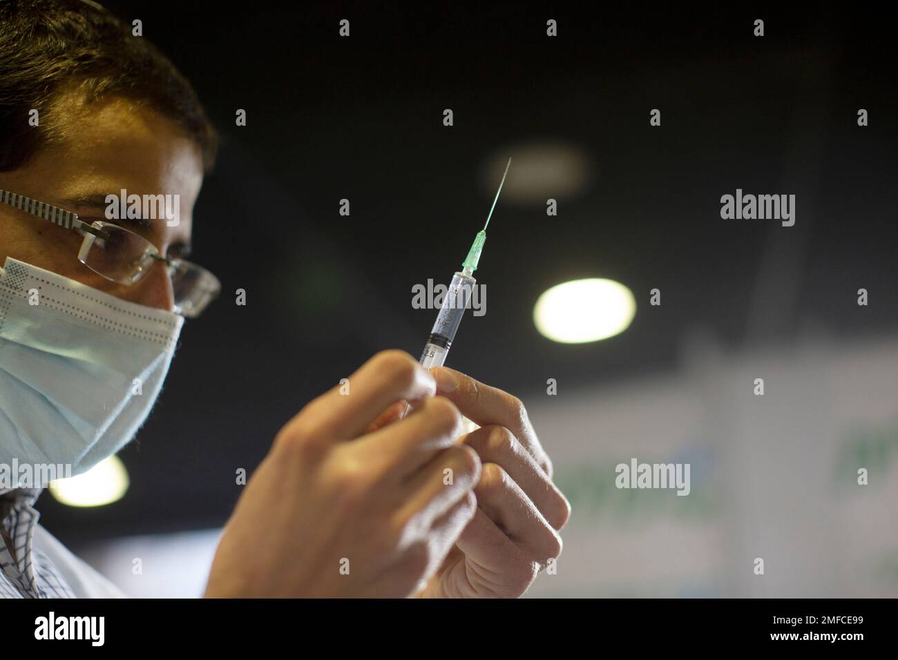 A medical professional prepares a syringe to administer the coronavirus ...
