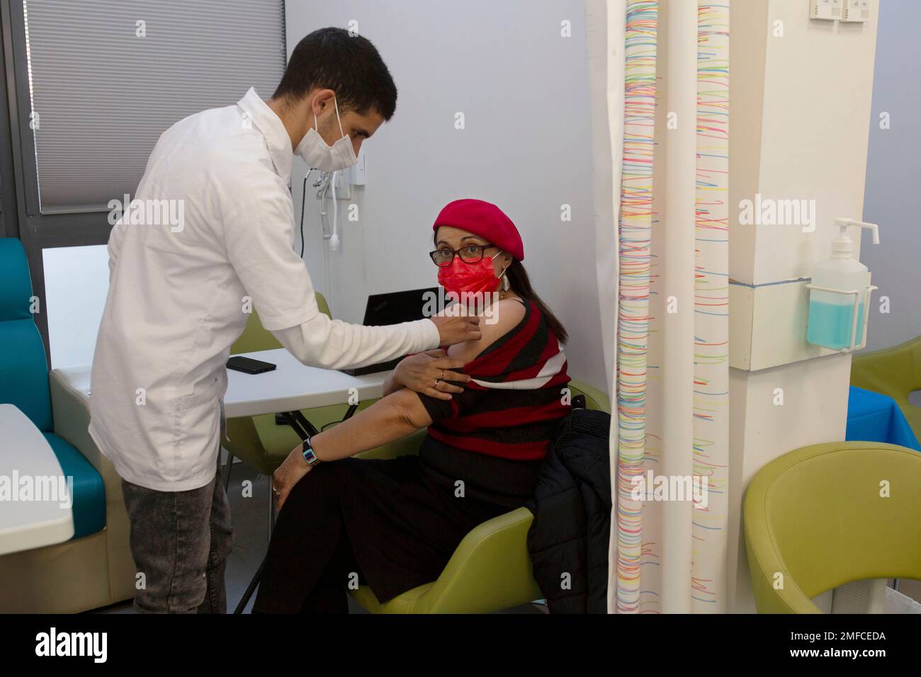 A nurse swabs a woman's arm before administering the coronavirus ...