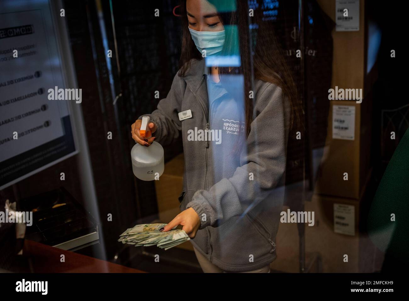 A turf accountant disinfects bills at the Hipodromo de la Zarzuela ...