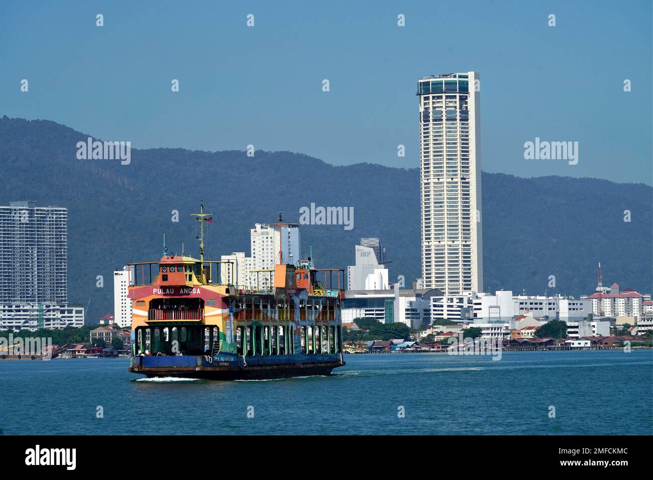 An iconic Penang ferry passes with a background of George Town of ...
