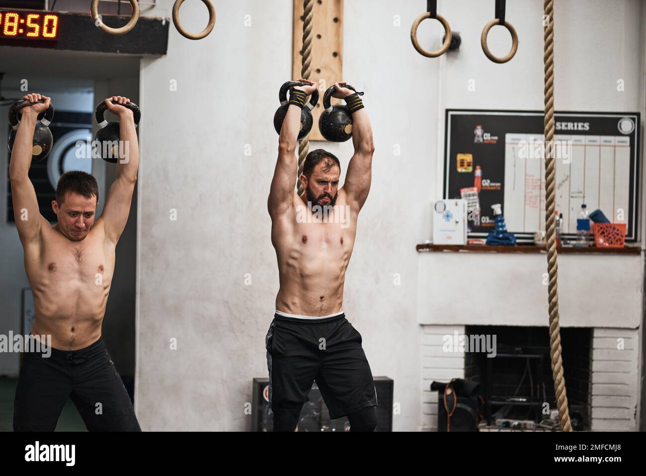 Loyal to getting our body in shape. young men lifting kettlebells in a ...