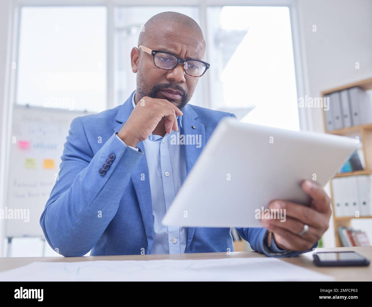 Black man, tablet and serious thinking face in office for web design ...