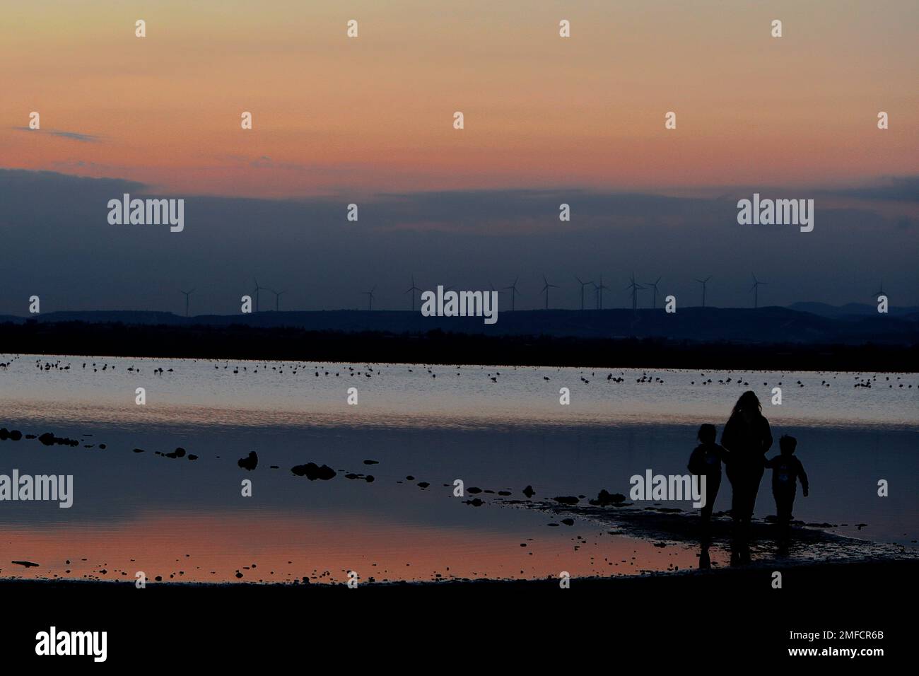 A mother with her two kids walk at the salt lake during sunset in ...