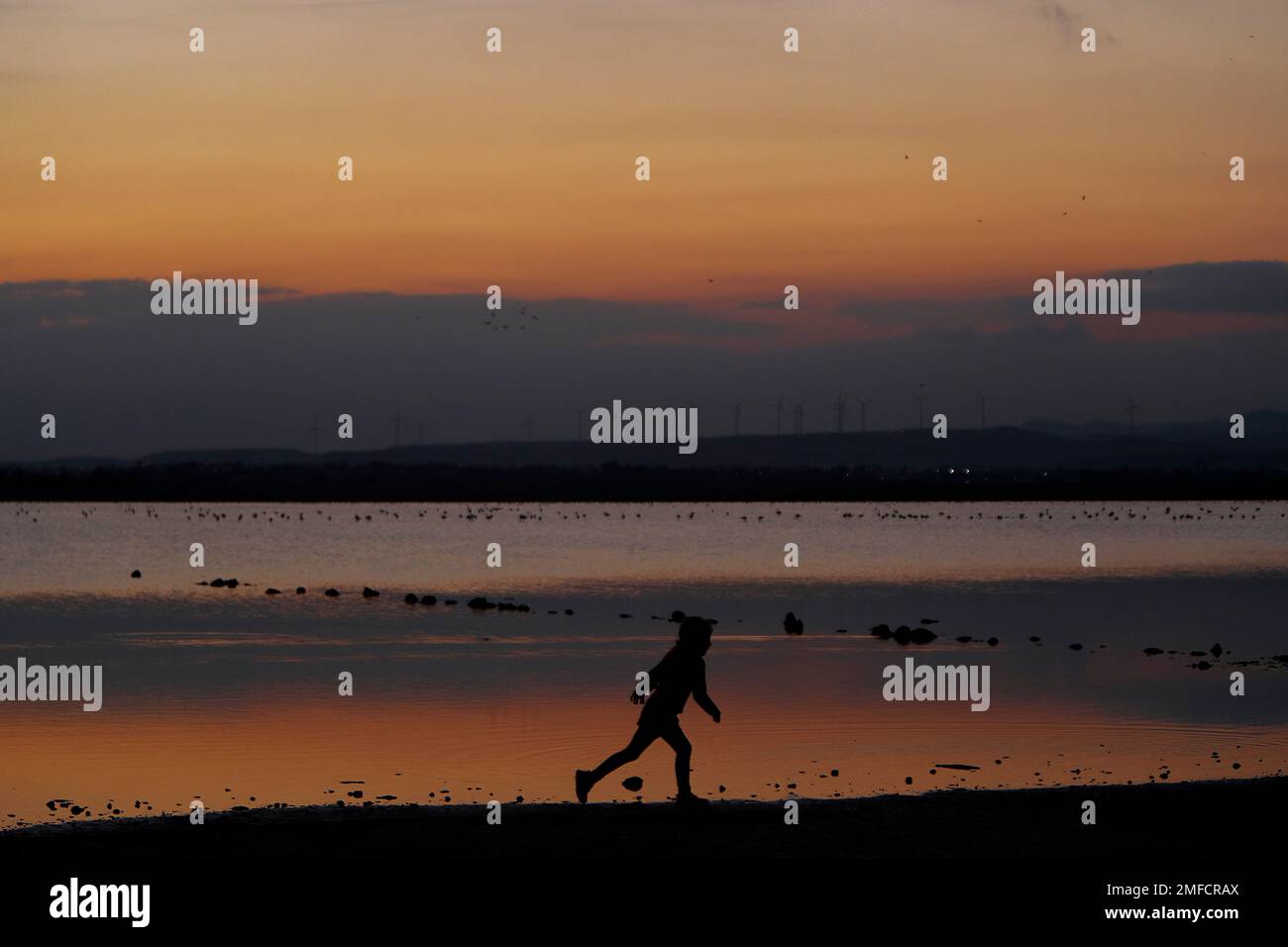 A little girl runs at the salt lake during sunset in southern coastal ...