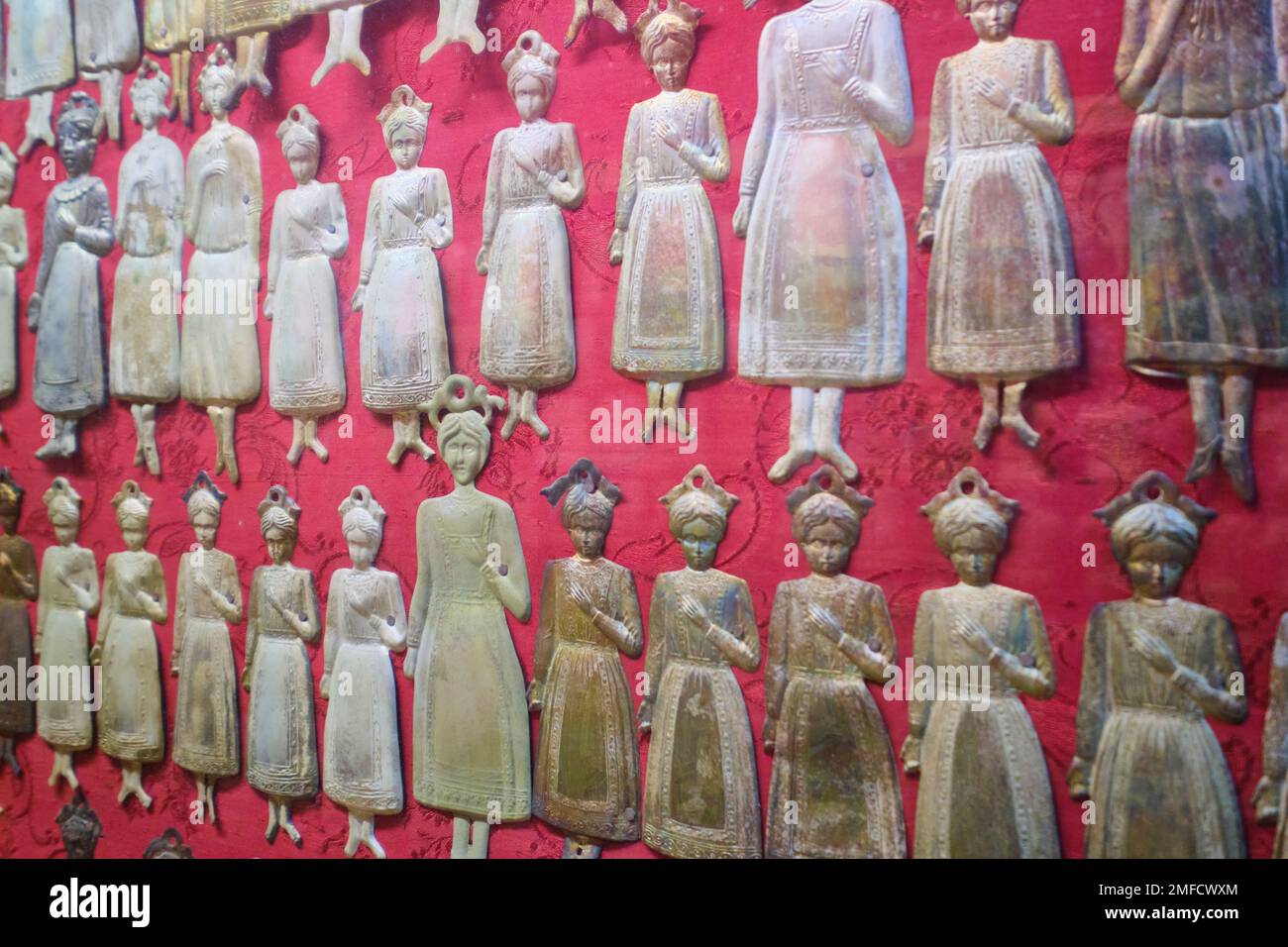 A wall of mounted votive offerings of tin, bronze, flat images of poor ...