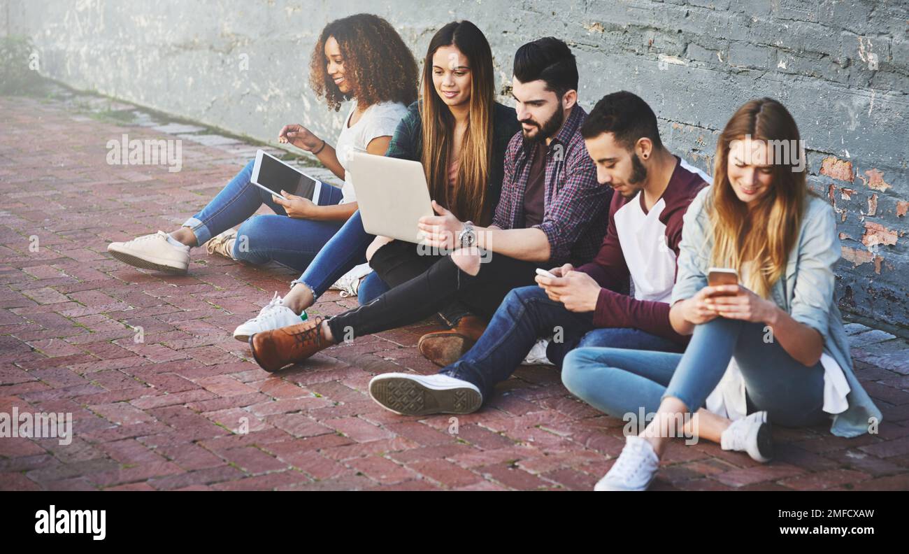 Connecting with peers. a group of young friends using their wireless ...