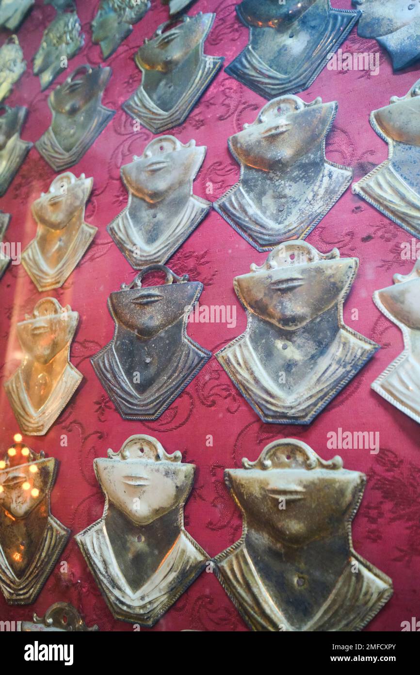 A wall of mounted votive offerings of tin, bronze, flat images of ...