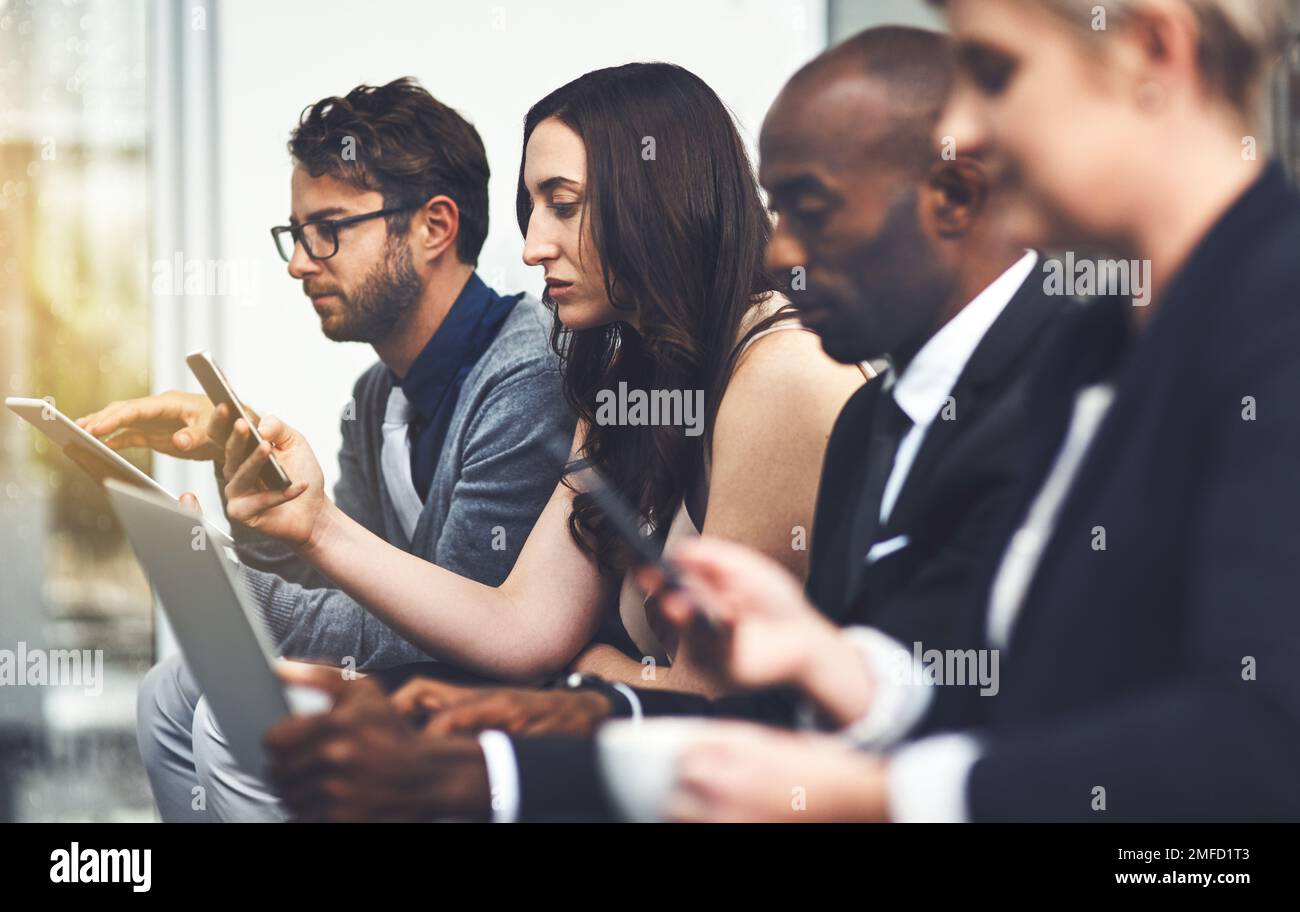 Its a busy office. a group of businesspeople using various digital ...