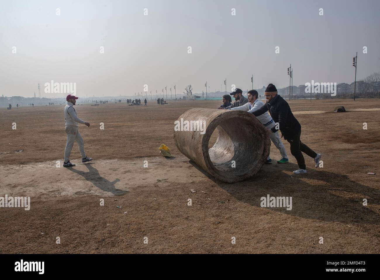 Kashmiri boys use cemented pipe as roller for even out cricket pitch ...