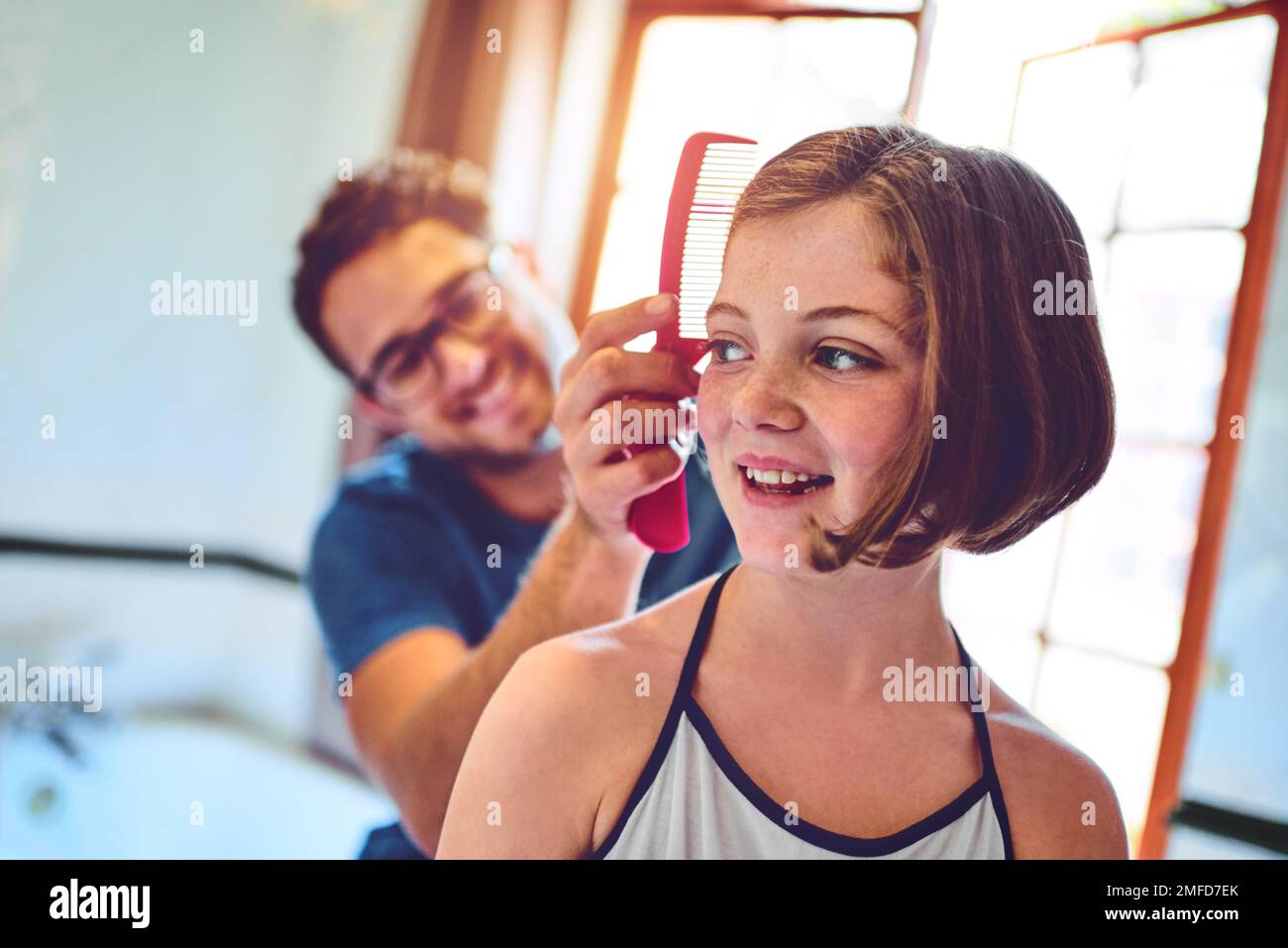 Dad makes the prettiest hairstyles. a father combing his little ...
