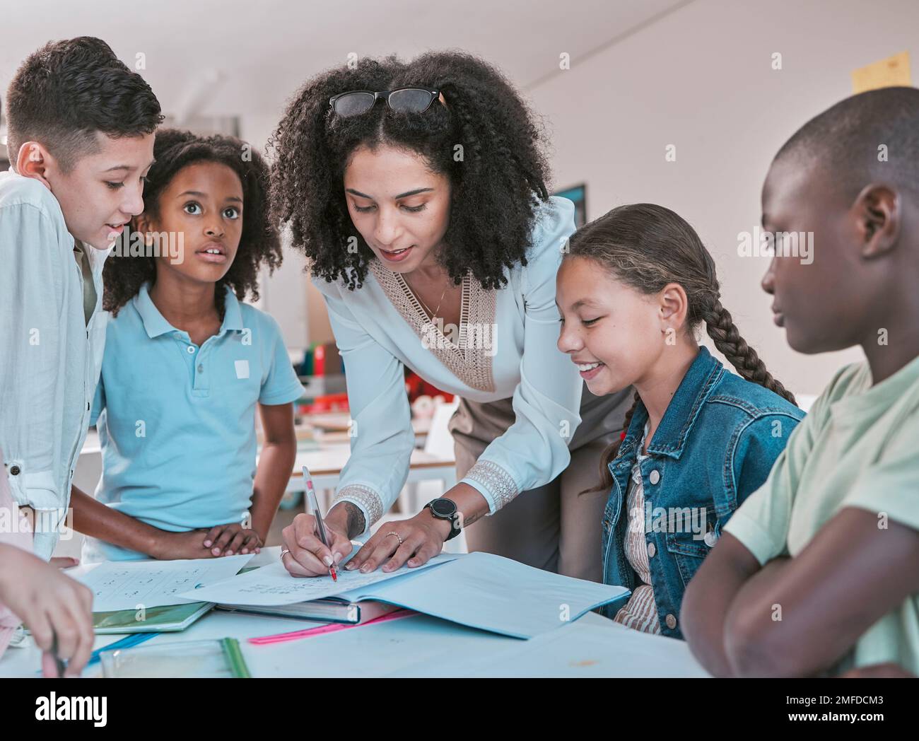 Female teacher in classroom with children, helping girl student with ...
