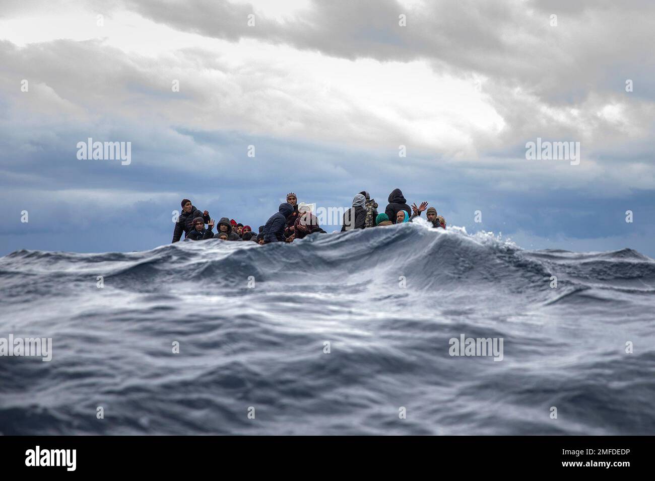 Migrants from Morocco and Bangladesh wait on an overcrowded wooden boat ...