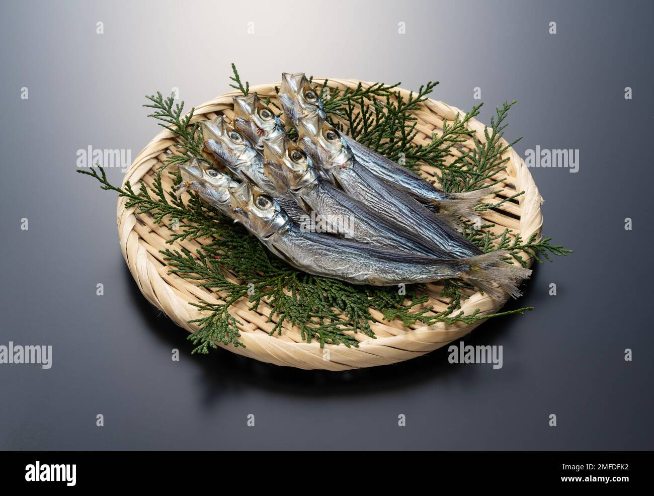 Ulmae sardines served in a colander placed on a black background ...