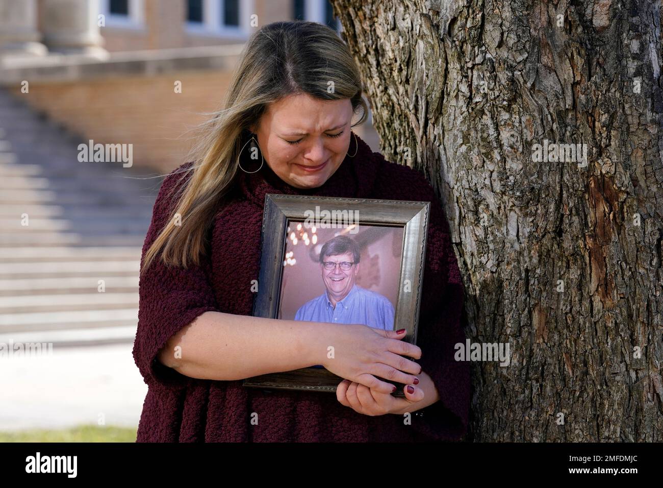 Katie Riggs Maxwell begins to cry as she hugs a portrait of her father ...