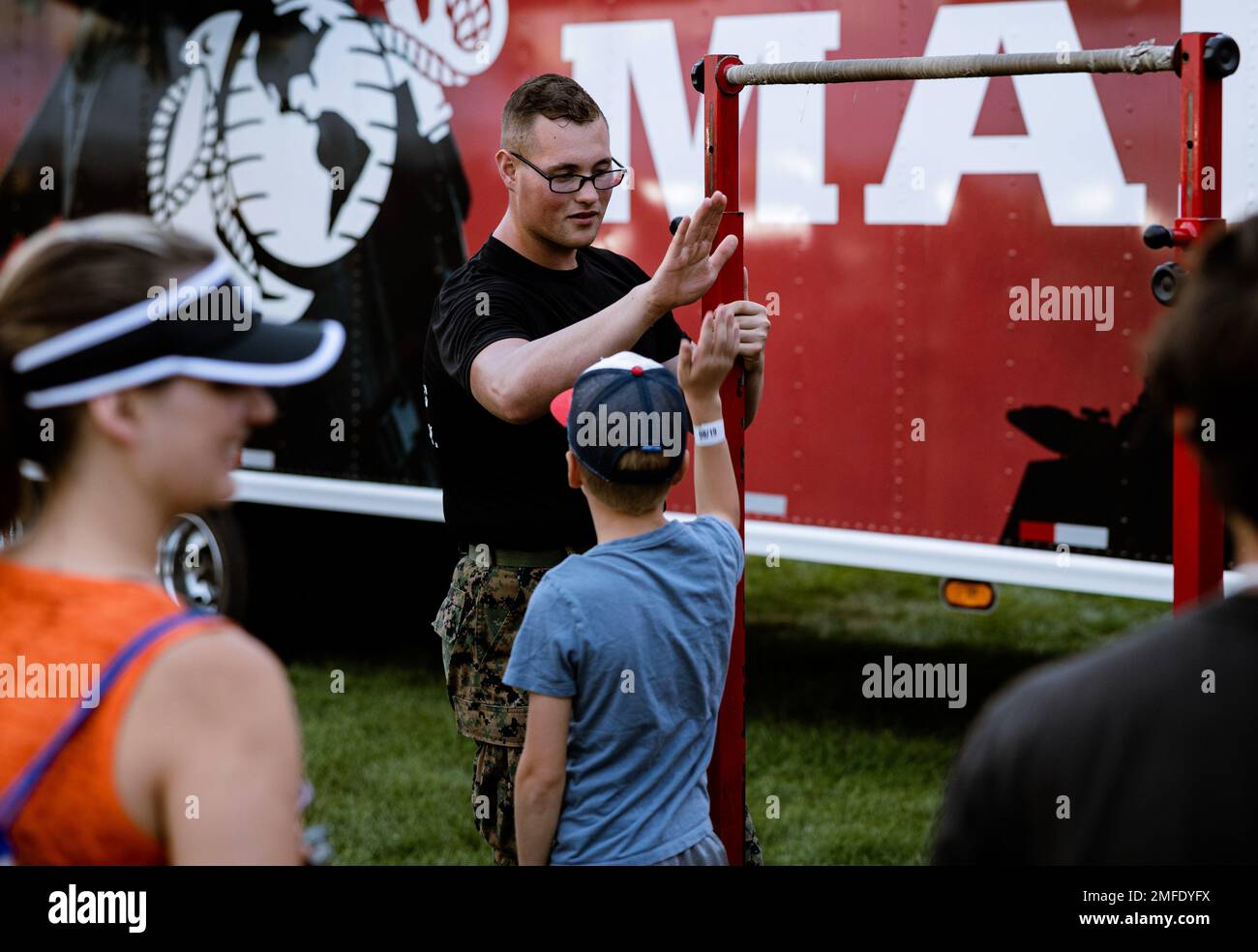 A U.S. Marine gives a child a high-five after attempting the pull-up ...