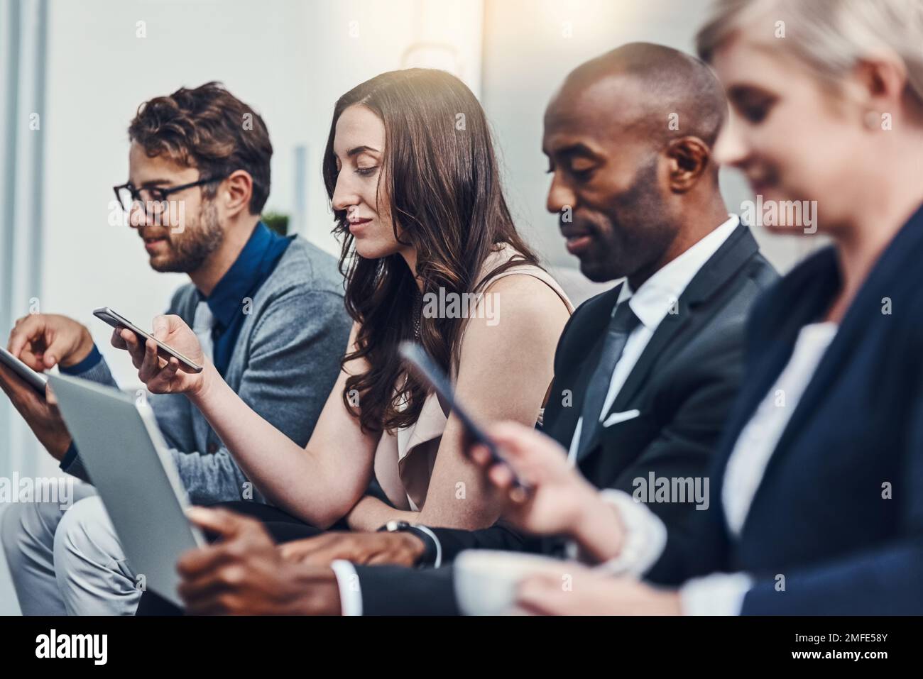 Its a busy office. a group of businesspeople using various digital ...
