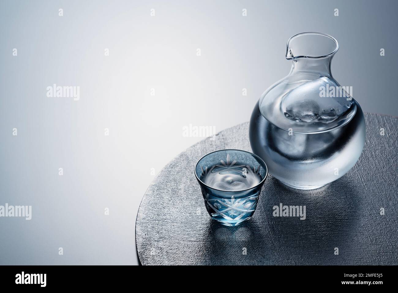 Sake poured into a faceted glass against a black background. The image ...