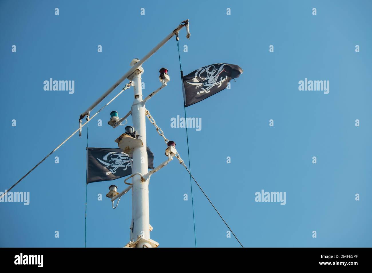 Jolly Roger or pirate ship flag waving with flagpole and blue sky ...
