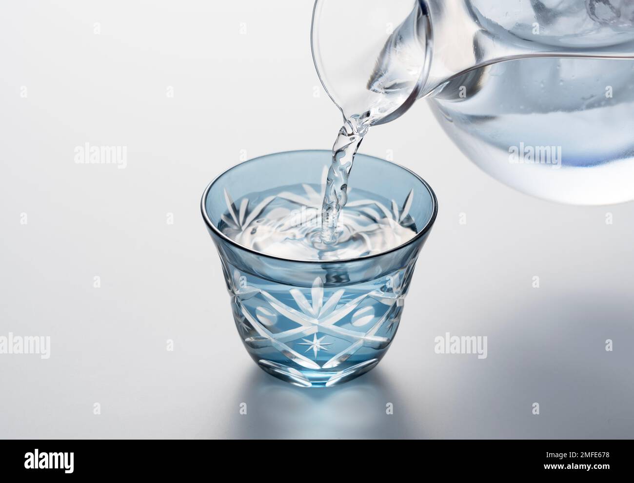 Sake poured into a faceted glass on a white background. The image of ...