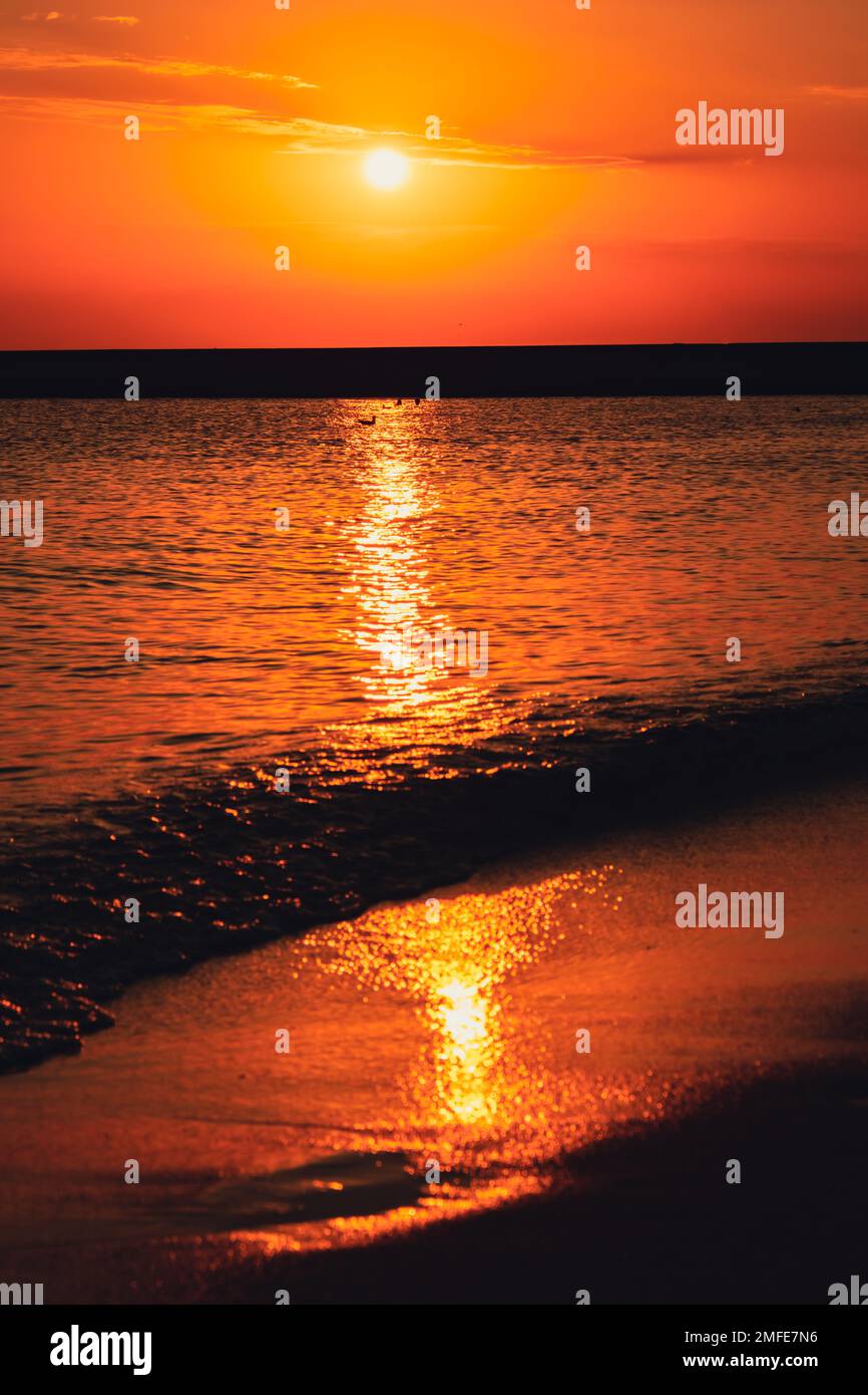 Reflection of sunlight over sea surface at sunset. Orange and gold blue ...
