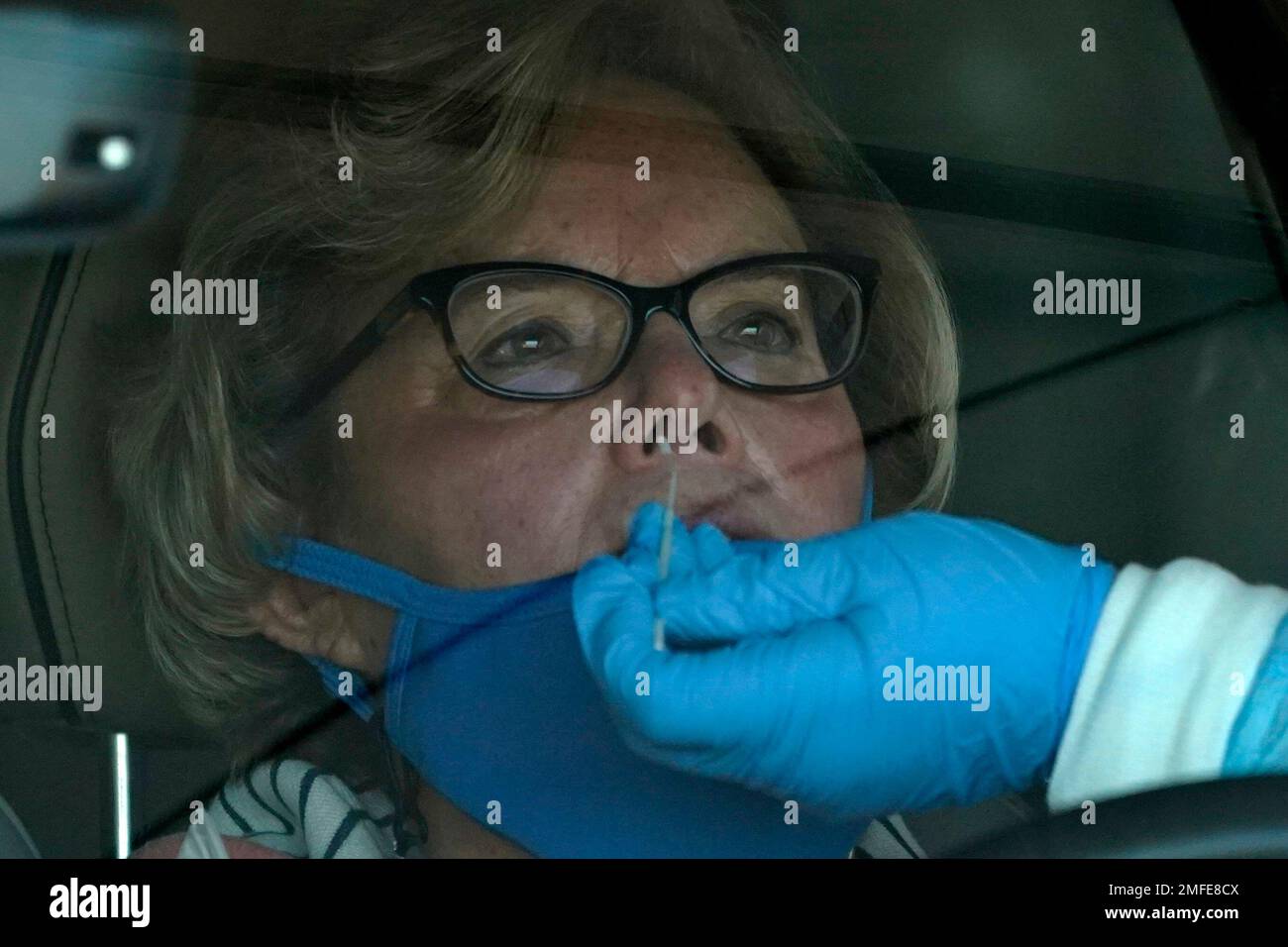 A health care worker collects a sample from a person at a drive-thru ...