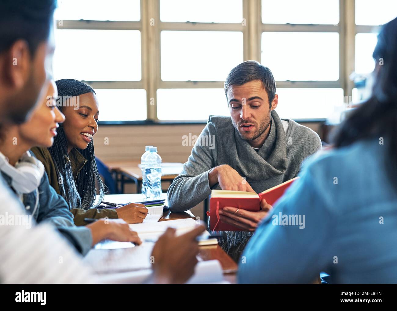 Hes helping them understand. a group of young university students ...