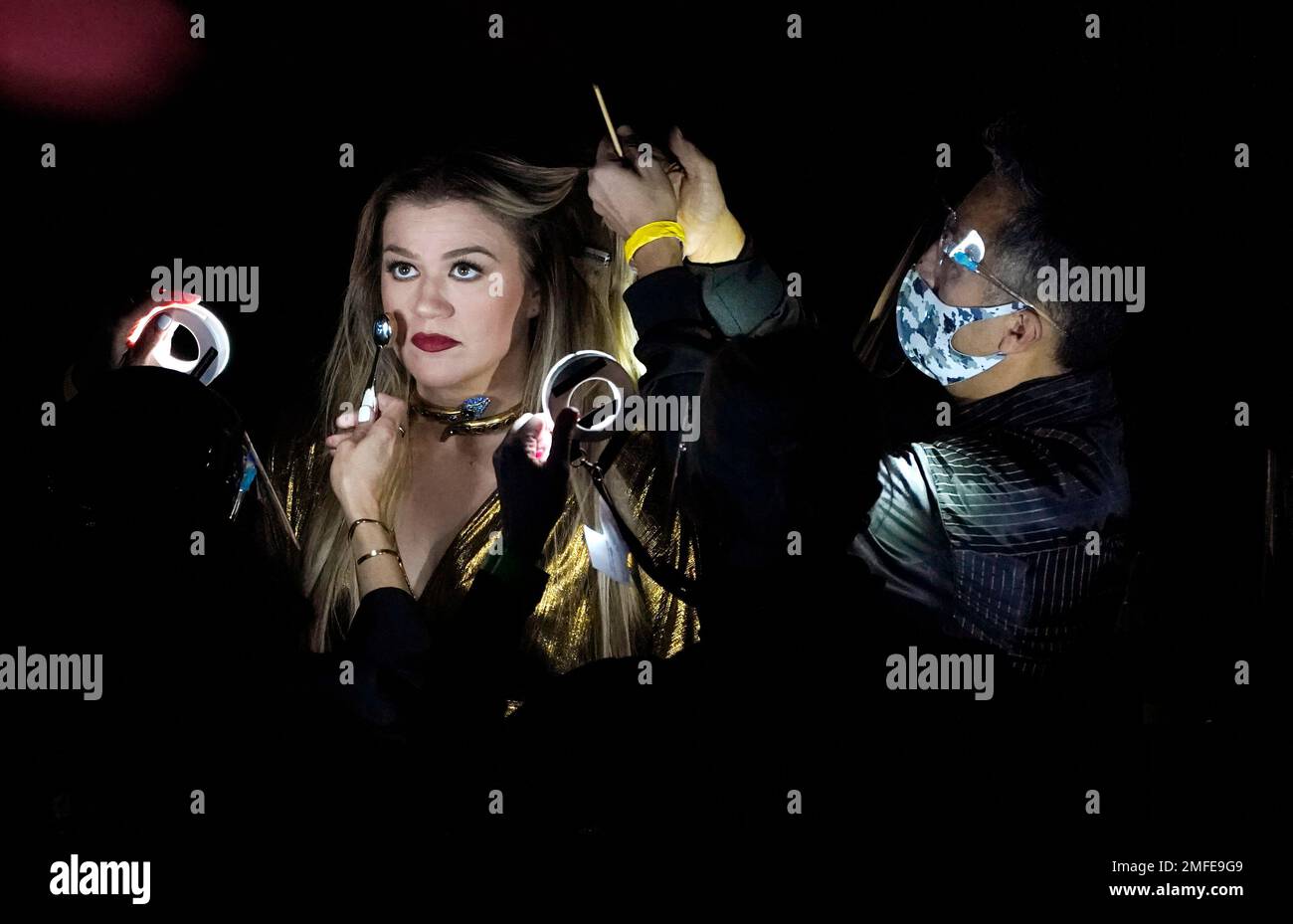 Masked crew members style host Kelly Clarkson during a commercial break ...