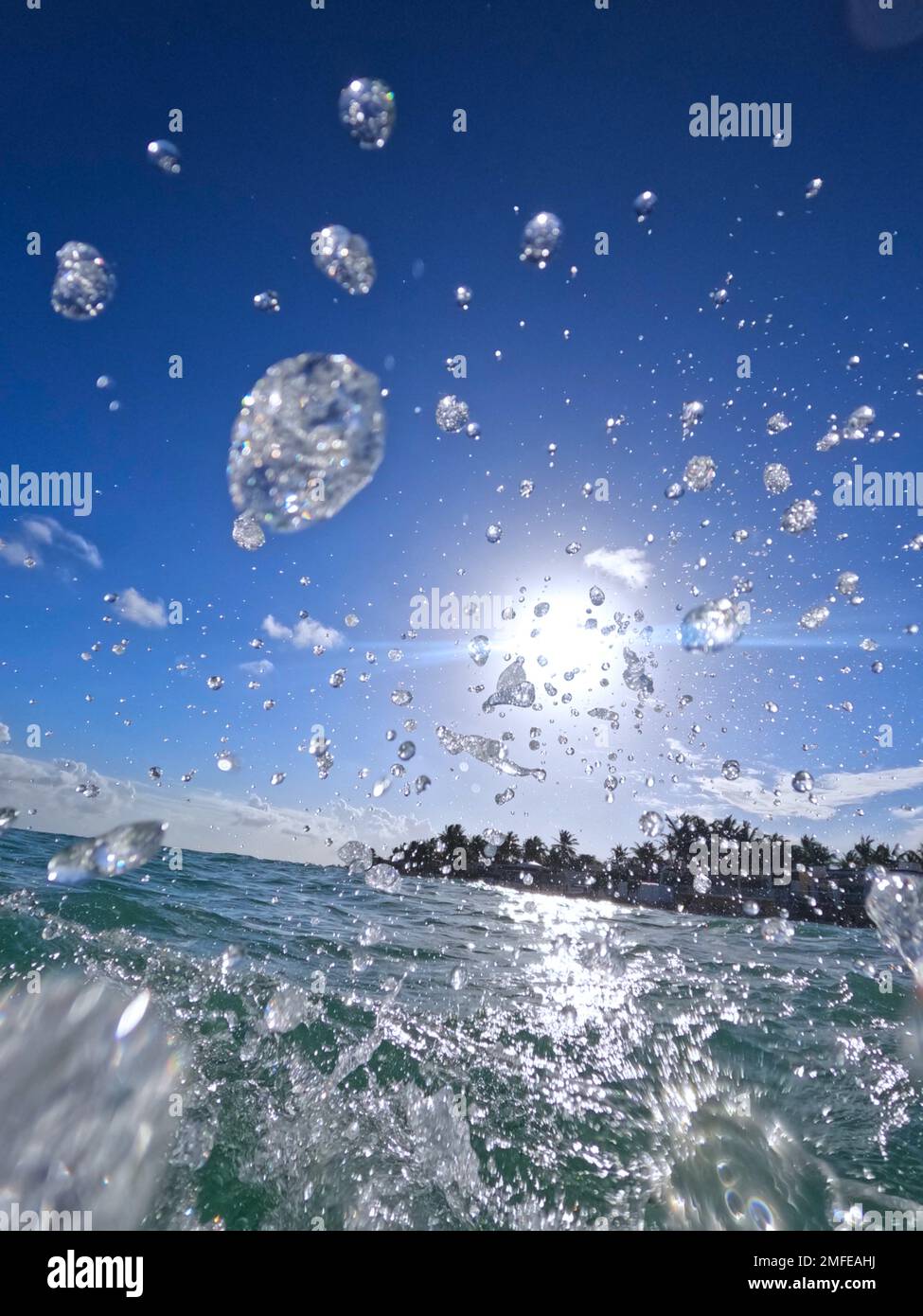 Water drops splash with sunny blue sky near the beach, vertical shot ...