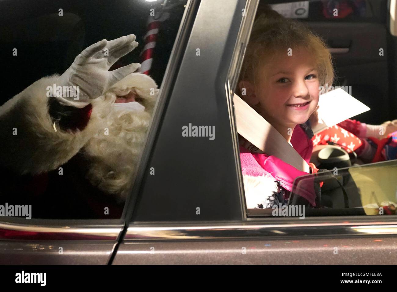 Brynn Brennan smiles at a social distant Santa as she rides past Santa ...