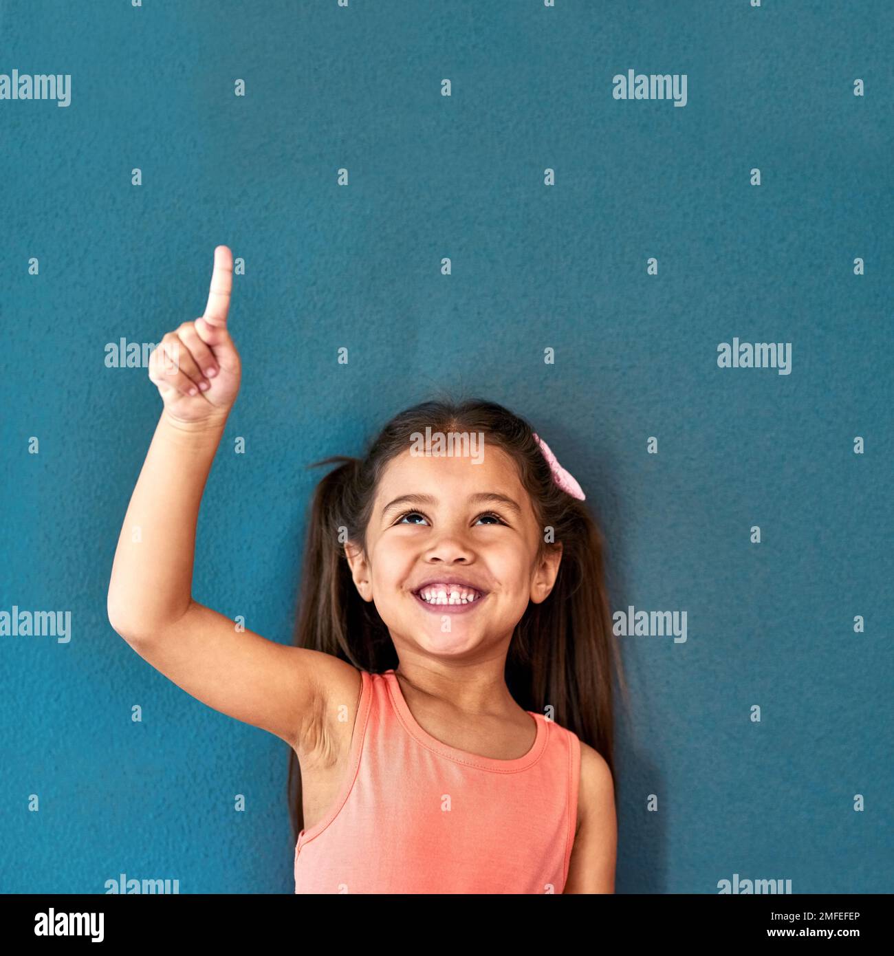 Look up there. Studio shot of an adorable little girl looking and ...