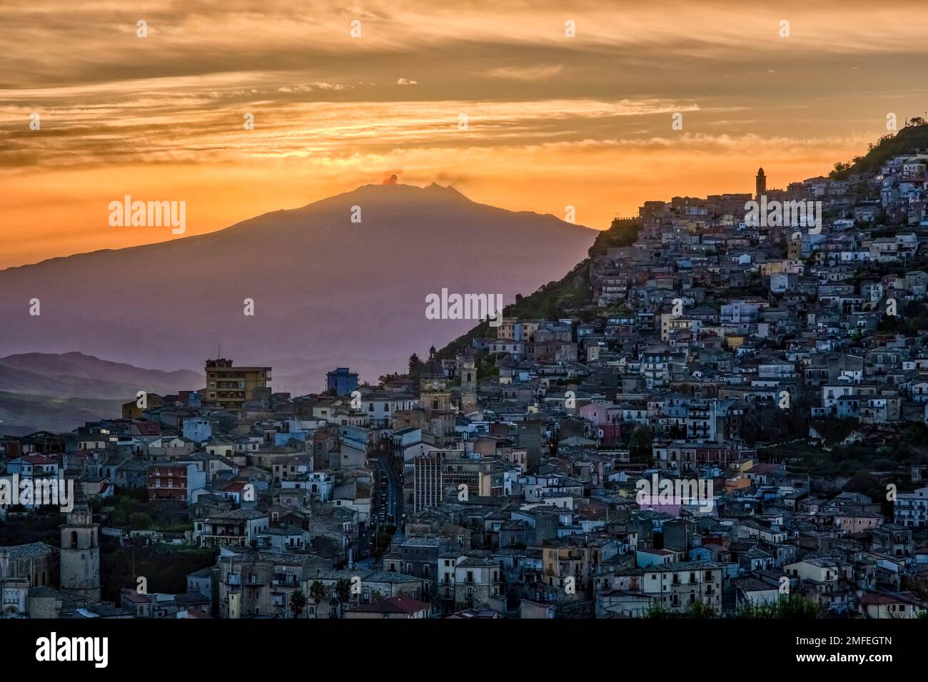 View of the town of Agira, situated on a hill, illuminated, the volcano ...